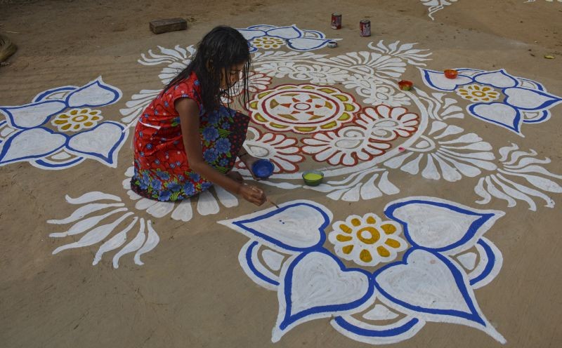 Agartala: A girl makes a 'rangoli' on the occasion of 'Makar Sankranti ...